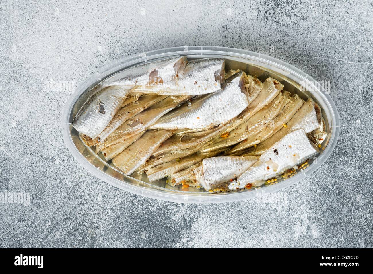 Pickled salted anchovies fillet set, in plastic container, on gray ...