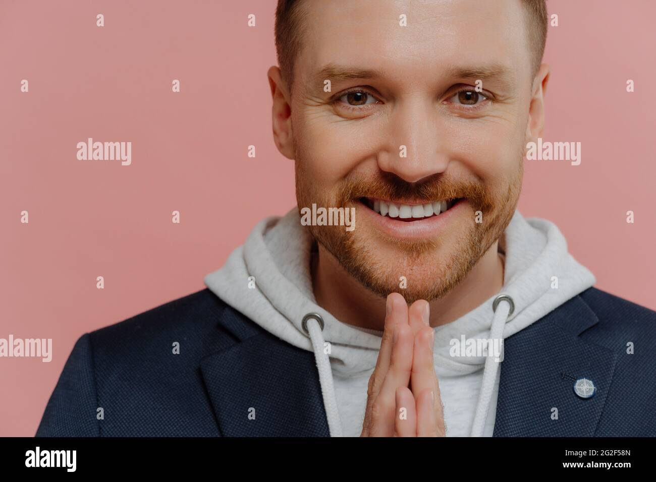 Happy man making praying gesture and smiling at camera Stock Photo - Alamy