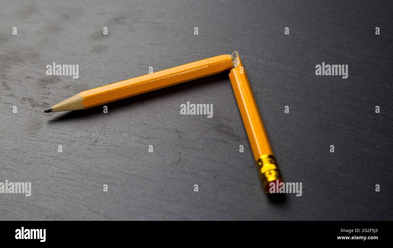 Broken into two parts yellow pencil a gray background Stock Photo - Alamy