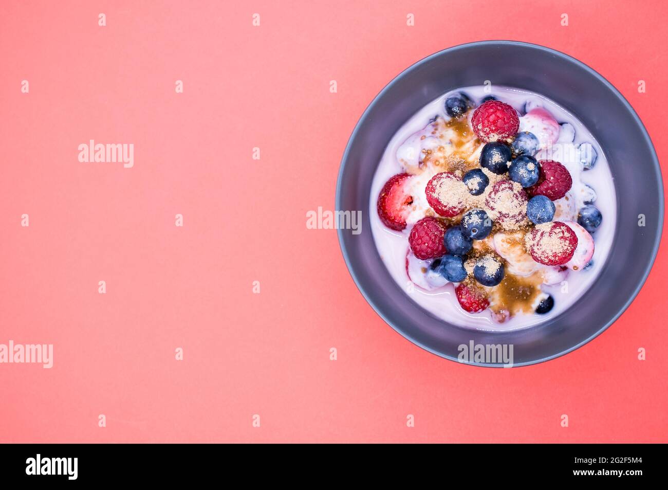 Top view of yogurt with raspberries, blueberries, and powder on a bowl ...