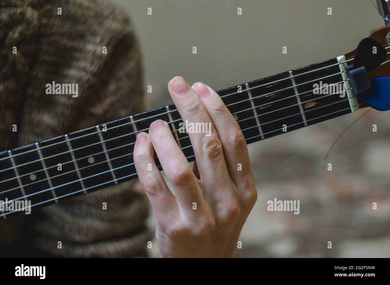 The musician plays the guitar. Fingers on a guitar fretboard close up ...