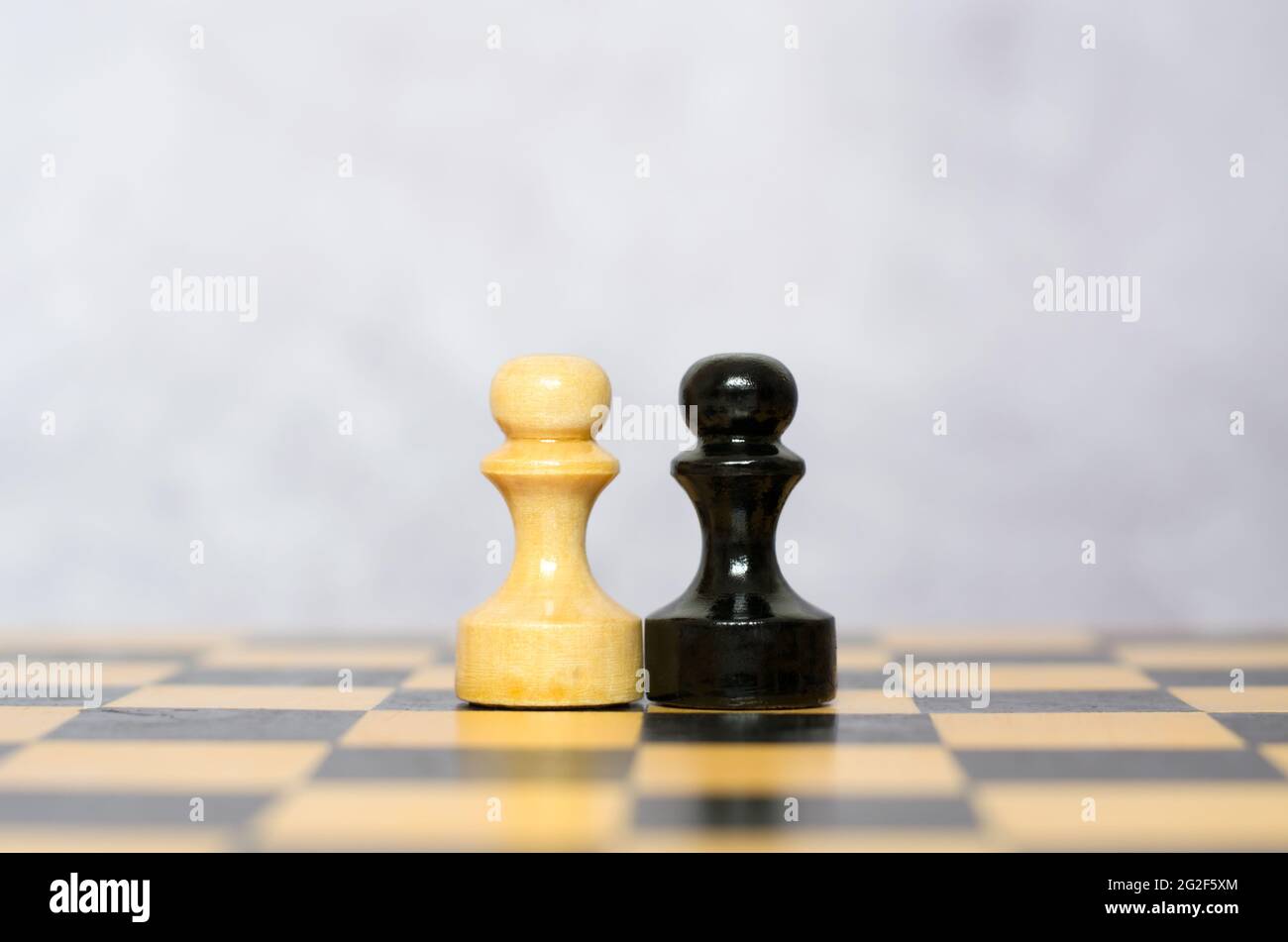 White and black wooden pawn on a chessboard. Chess pieces, side view ...
