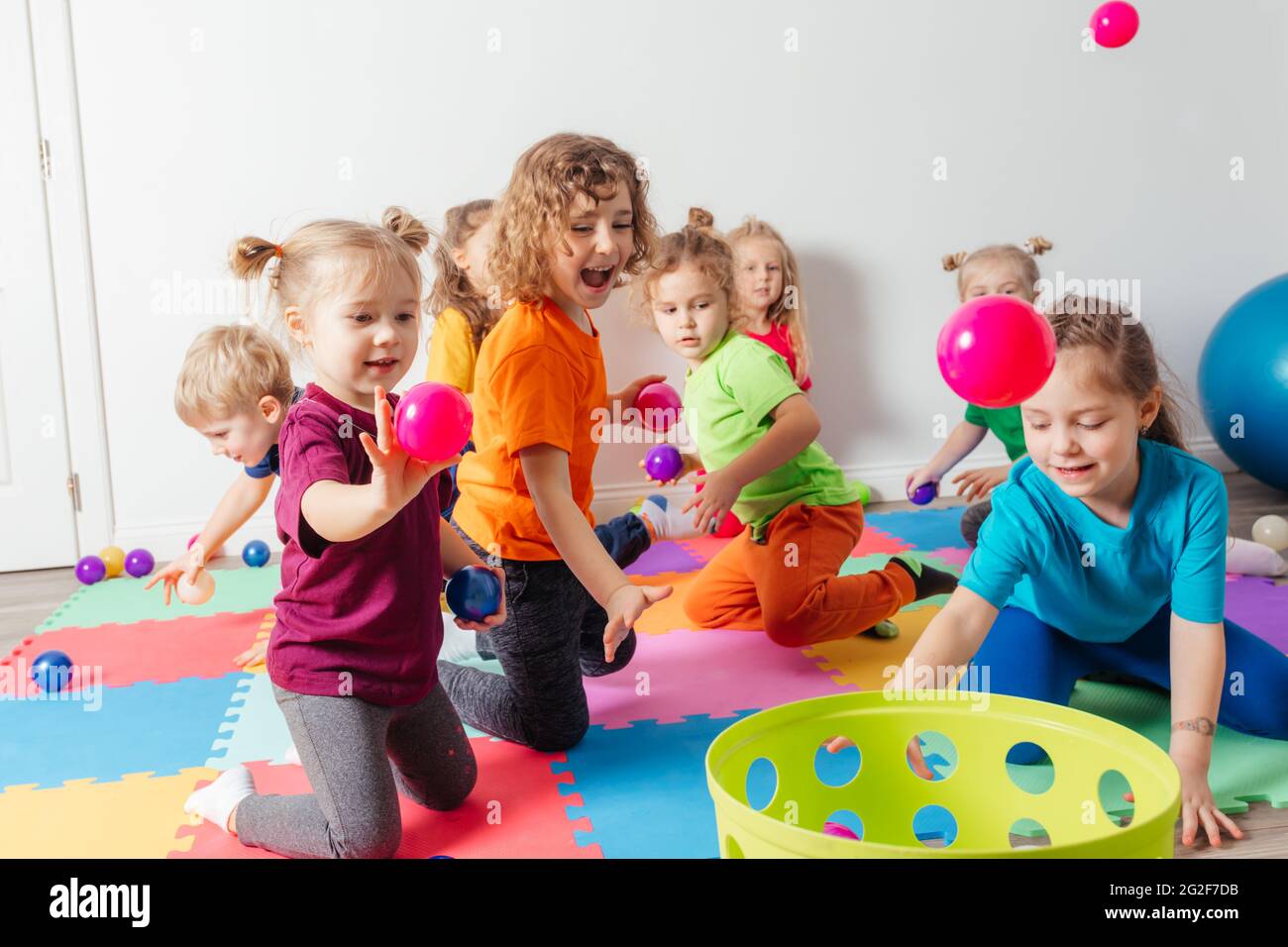 Happy kids throwing balls into plastic basket Stock Photo - Alamy