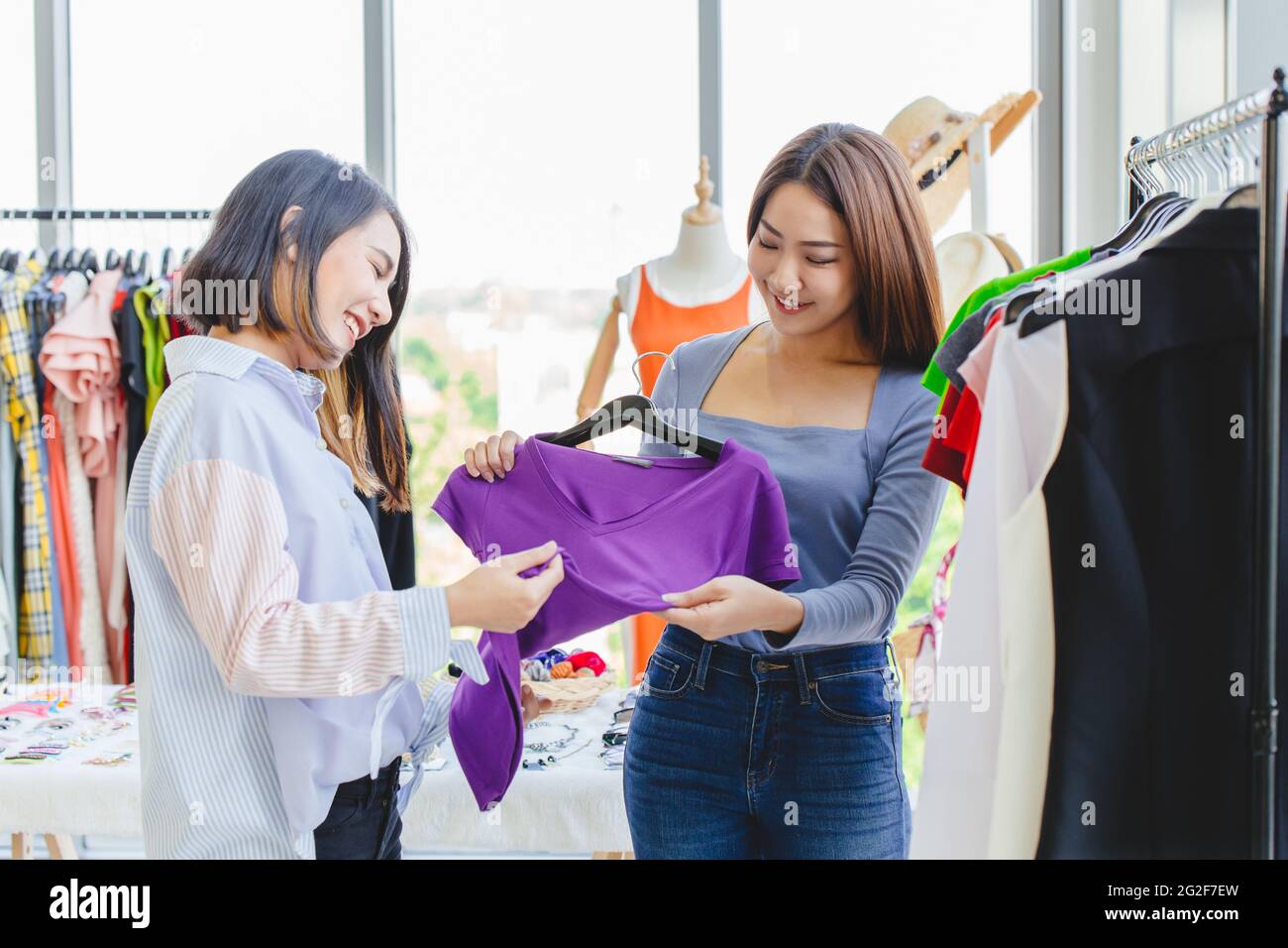 Women customer choosing clothes in fashion shop with business owner ...