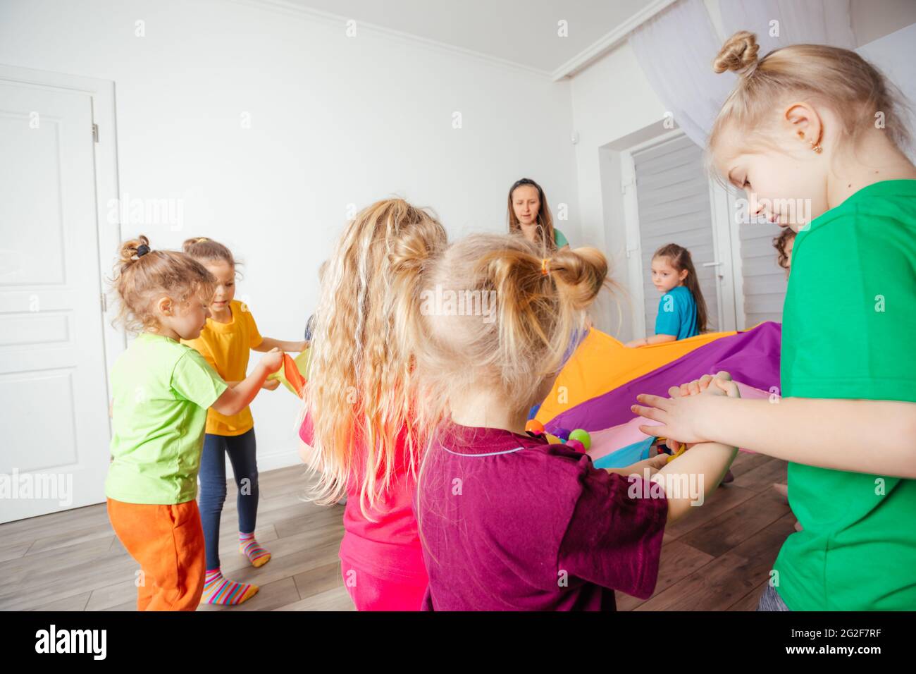 Teacher and kindergarten kids playing with colorful parachute Stock ...