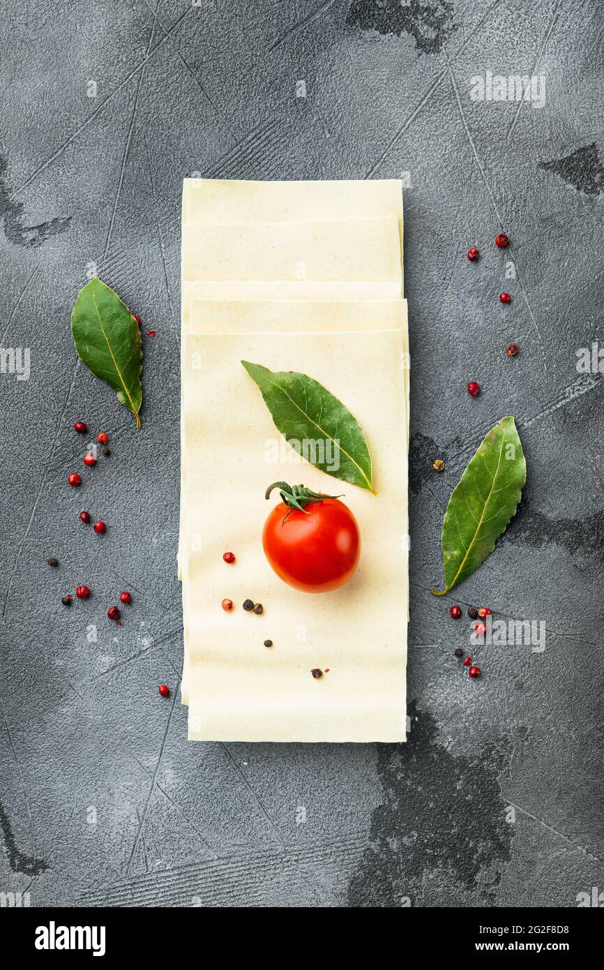 Uncooked lasagna sheets set, with seasoning and herb, on gray stone ...