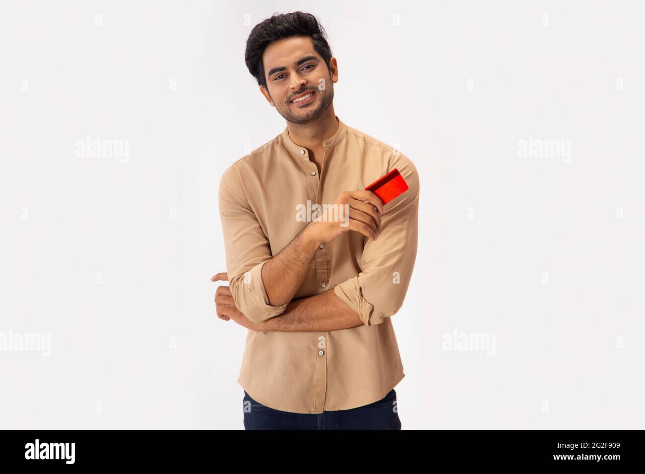 A CHEERFUL YOUNG MAN STANDING WHILE HOLDING DEBIT CARD IN HAND Stock ...