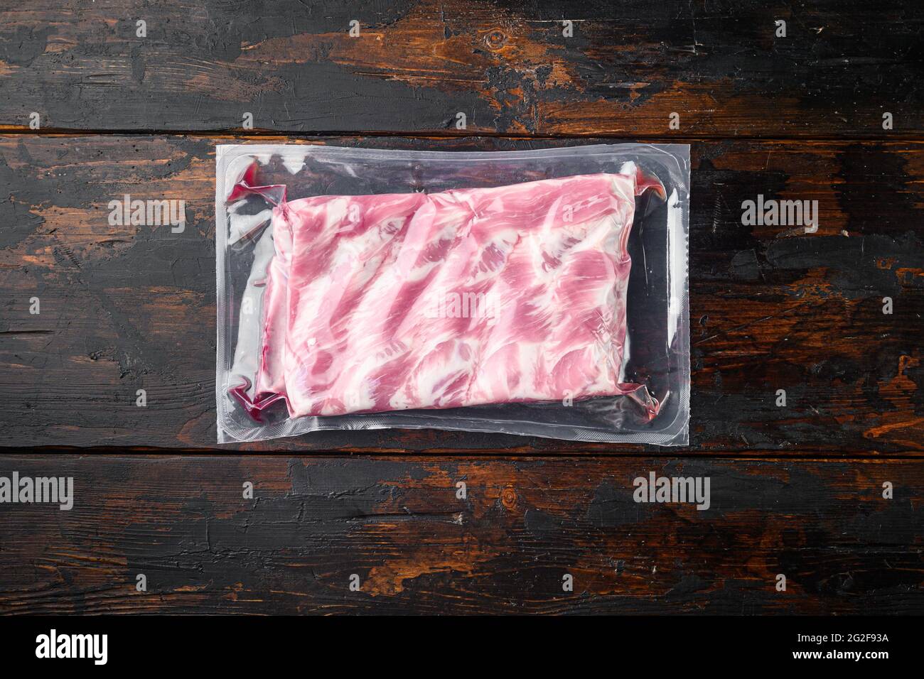 Vacuum packaging with raw pork rib set, on old dark wooden table ...