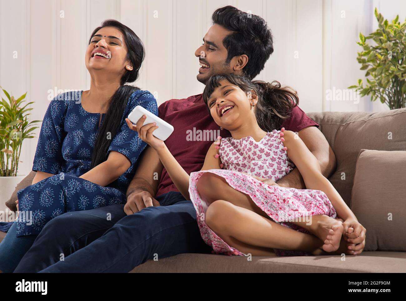 A CHEERFUL FAMILY HAPPILY LAUGHING TOGETHER WHILE SITTING COMFORTABLY ...