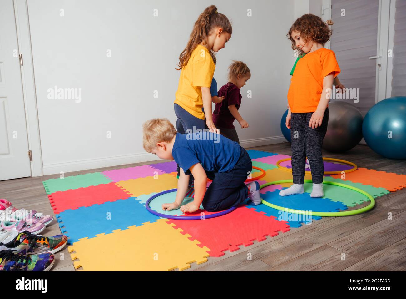 Children running and jumping around multicolor hoops on a floor Stock ...