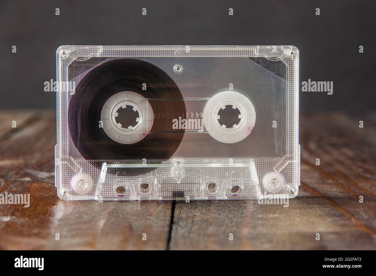 An audio cassette in a transparent scratched case stands on a brown ...