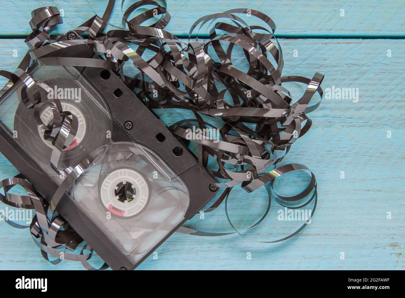 On a blue wooden background, there is an audio cassette with an unwound ...
