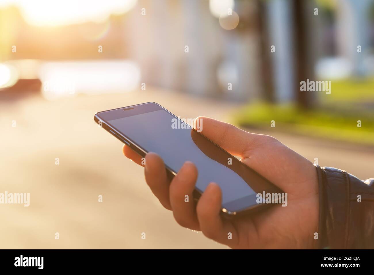 Man uses his Mobile Phone outdoor, close up. Men hand holding texting ...
