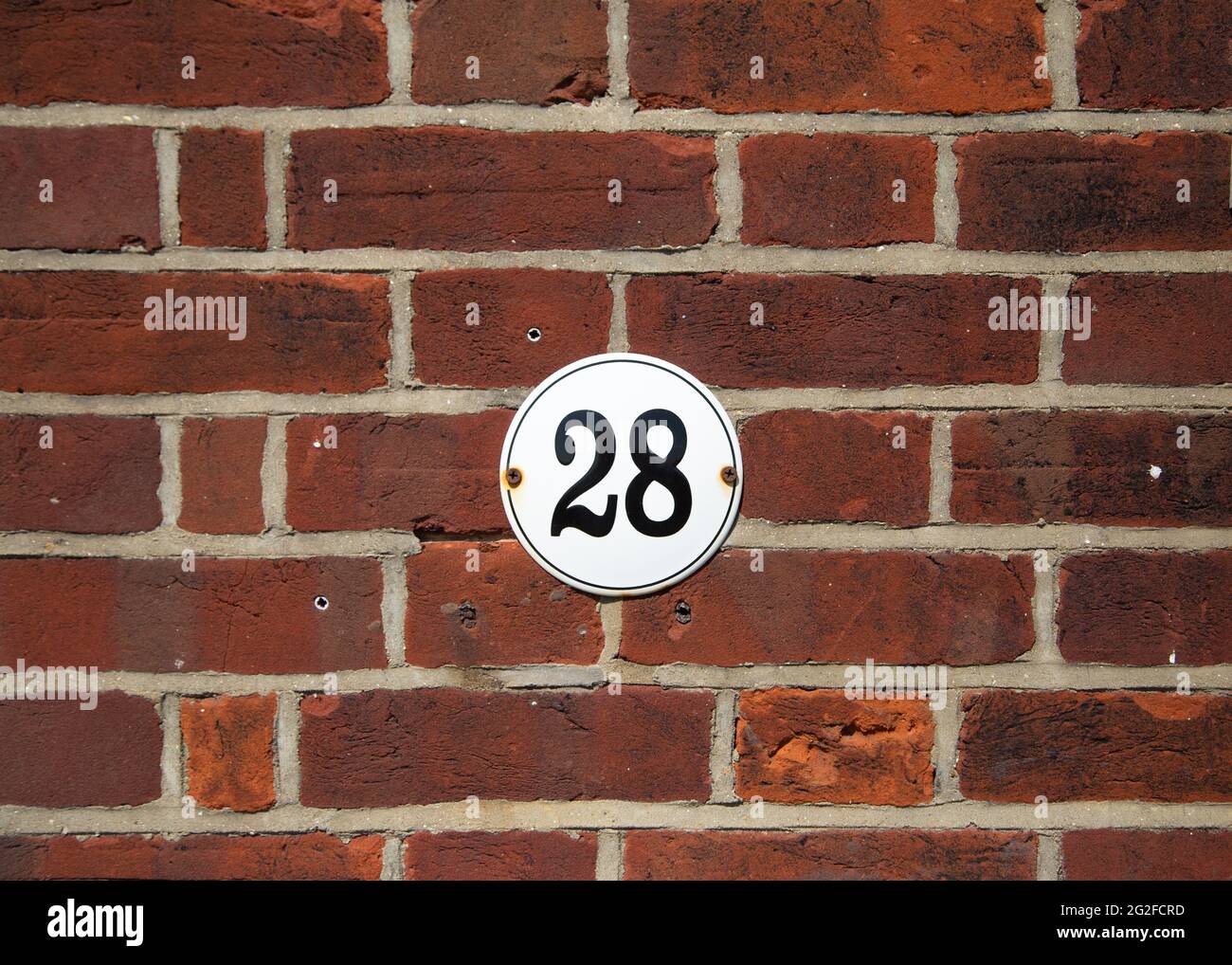 Number 28 on old red brick wall. Black number 28 on white round house ...