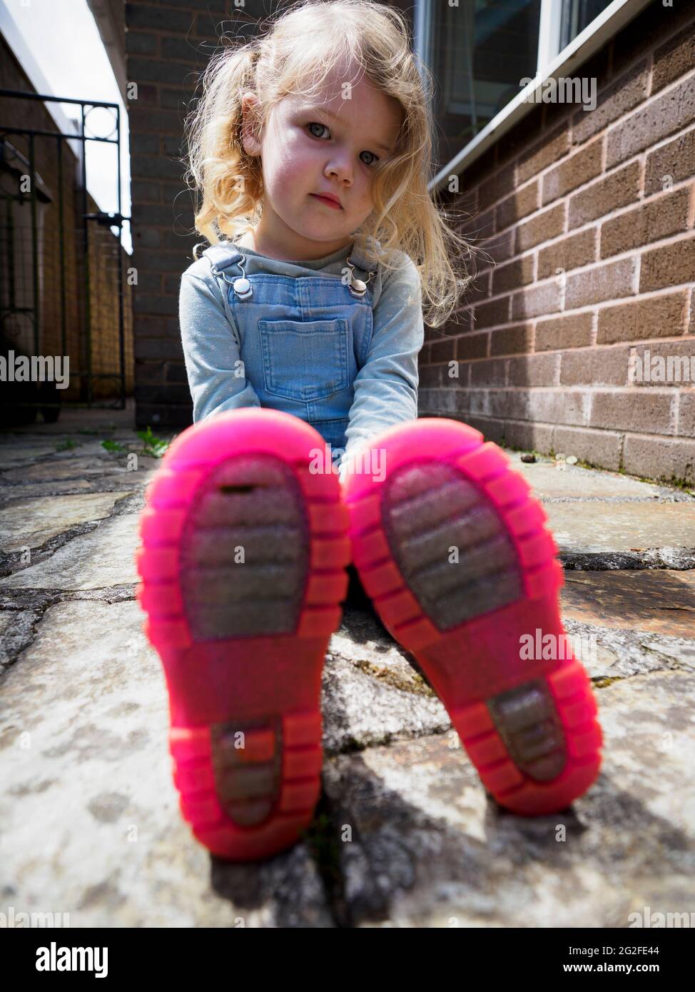 Young child sat on the floor outside, Devon, UK Stock Photo - Alamy