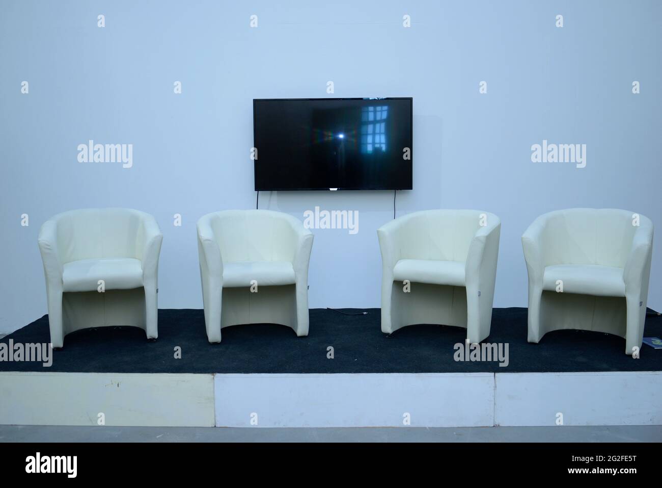 An interactive empty room: white chairs placed on stage and monitor ...