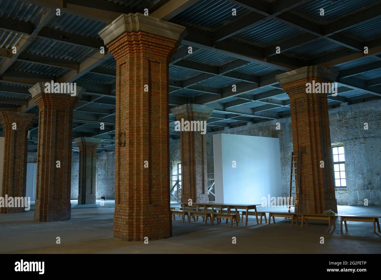 Large empty hall under construction. Brick pillar columns, ladder ...