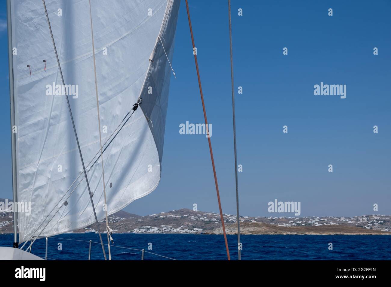 White sloop rigged yacht sailing in open calm ocean, blue sky ...