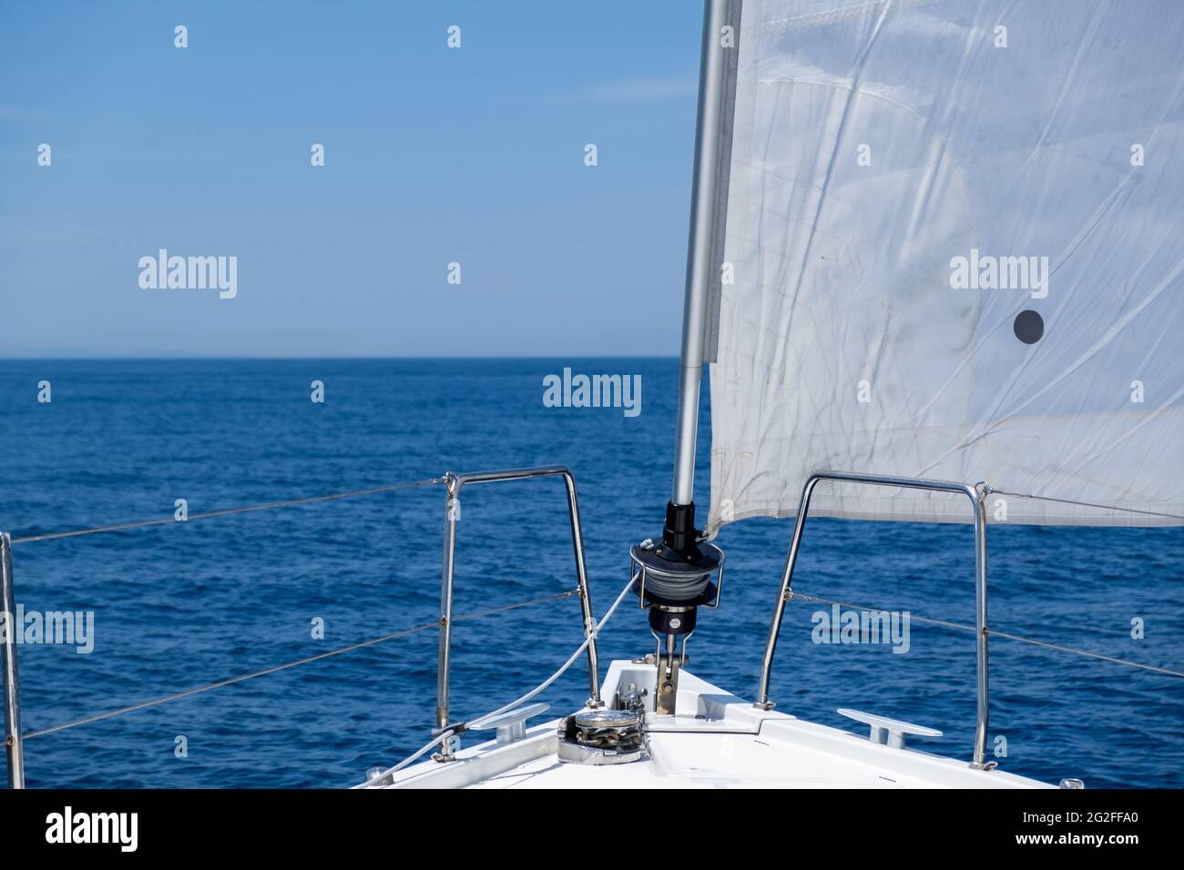 White sloop rigged yacht sailing in open calm ocean, blue sky ...