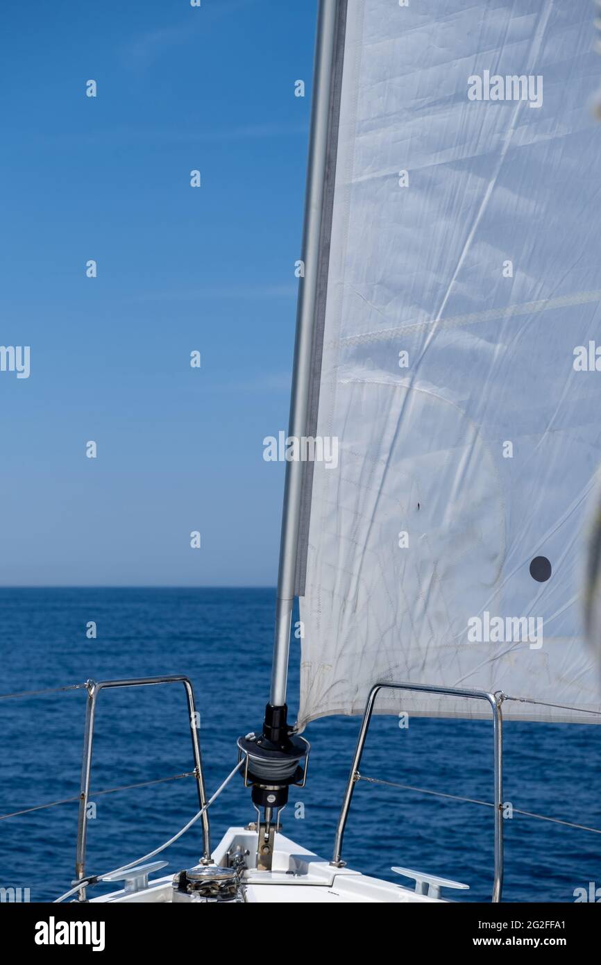 White sloop rigged yacht sailing in open calm ocean, blue sky ...