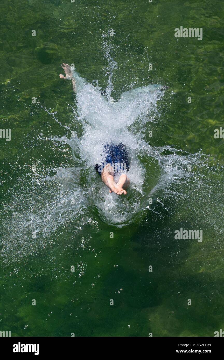 Dresden, Germany. 11th June, 2021. A boy jumps into the water from a ...