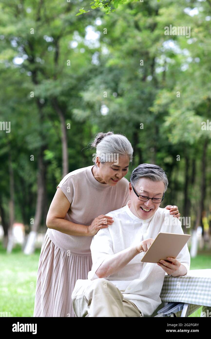 Happy elderly couples use tablet computers to surf the Internet ...
