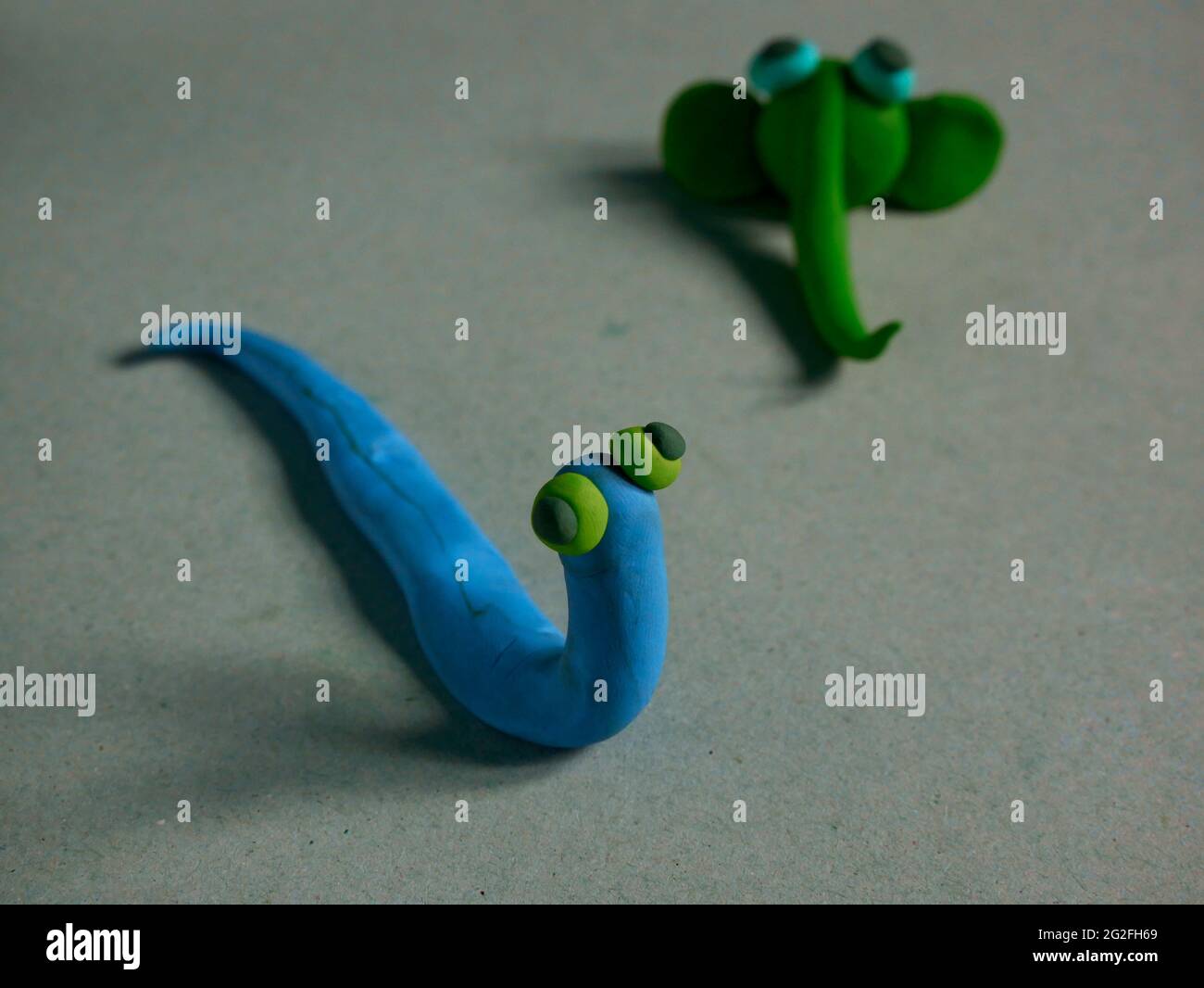 Clay made blue color snake standing on funny posture with blur green ...