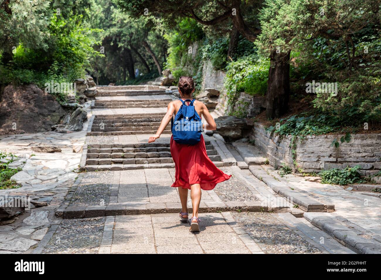 Happy backpacker running having fun in summer palace gardens in Beijing ...