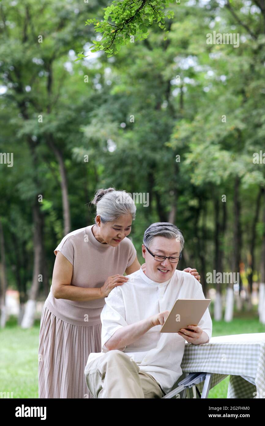 Happy elderly couples use tablet computers to surf the Internet ...