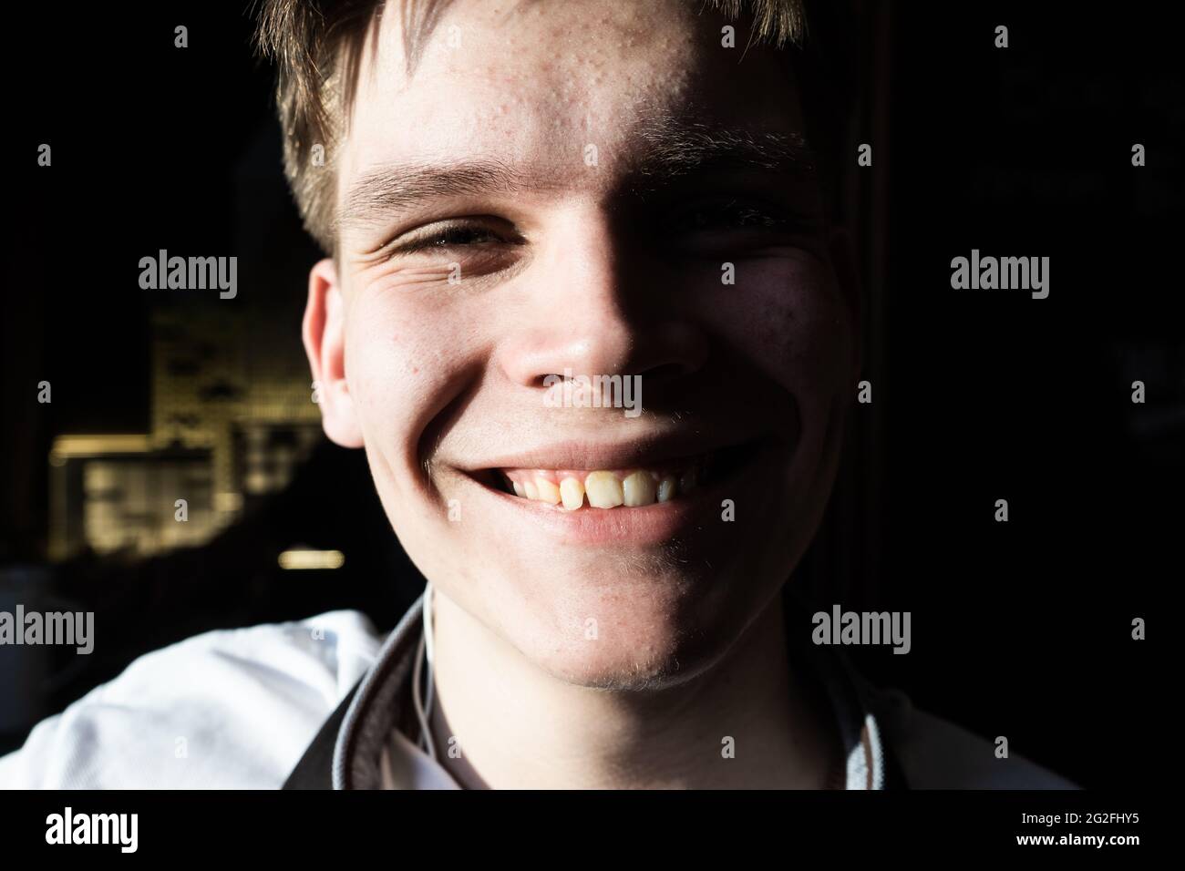 portrait of a smiling young man in a white shirt. bright side sunlight ...