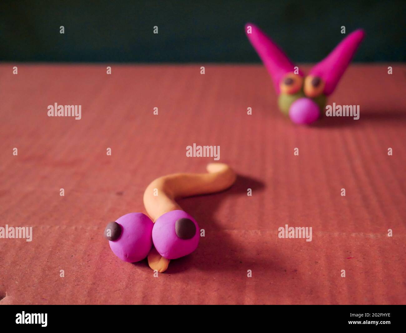 Funny clay snake big eyes isolate on brown cardboard Stock Photo - Alamy