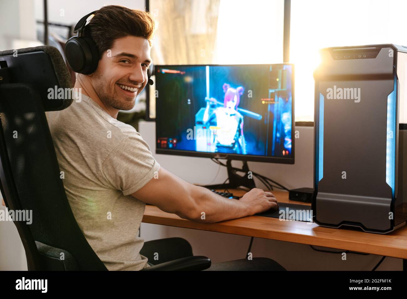 Happy brunette guy in headphones playing video game on his computer ...