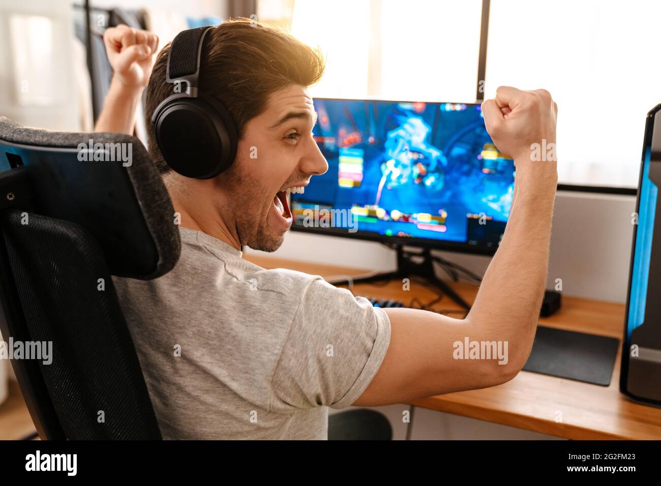 Excited guy in headphones making winner gesture while playing video ...