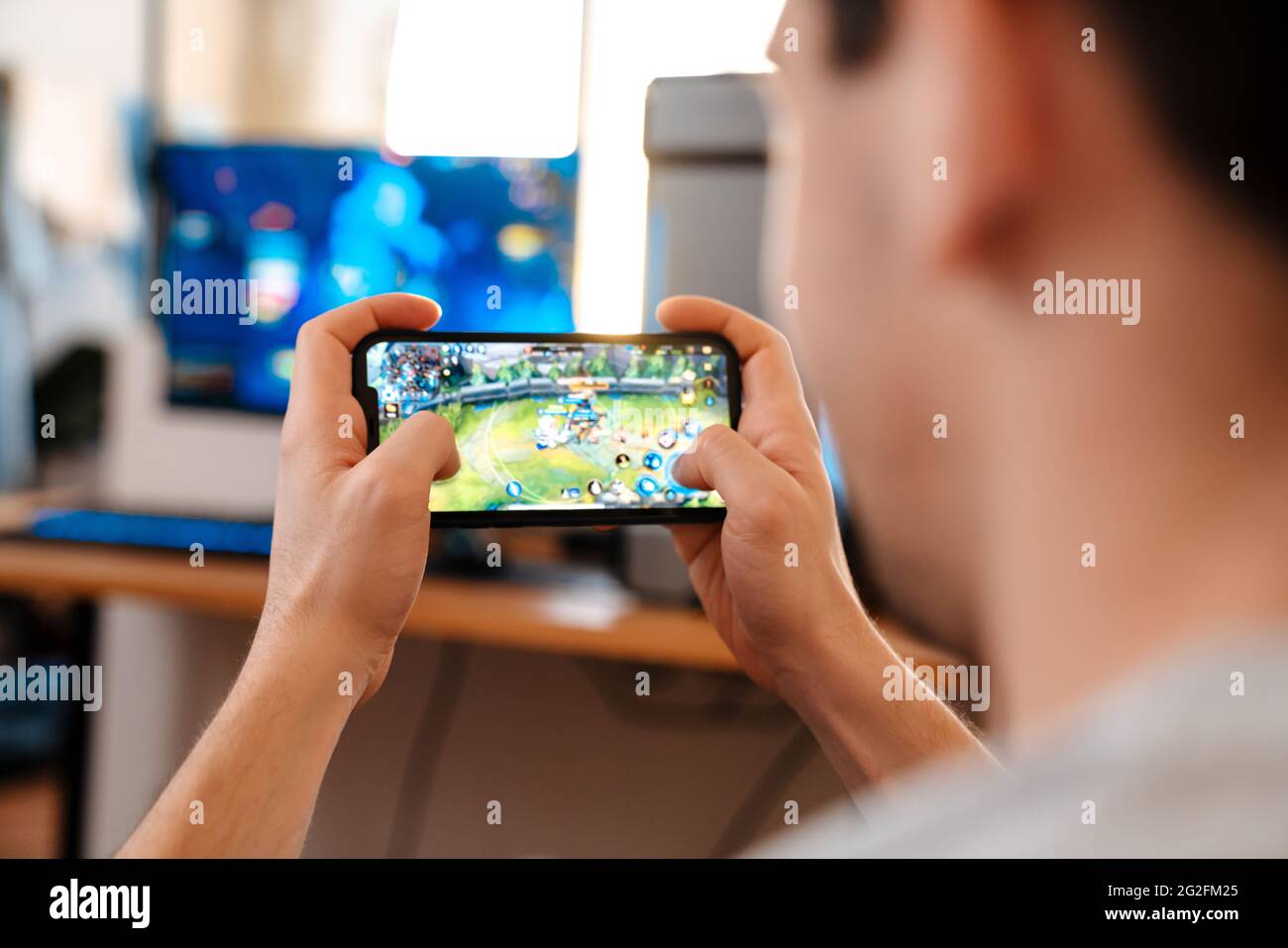 Unshaven brunette guy playing video game on his mobile phone at home ...