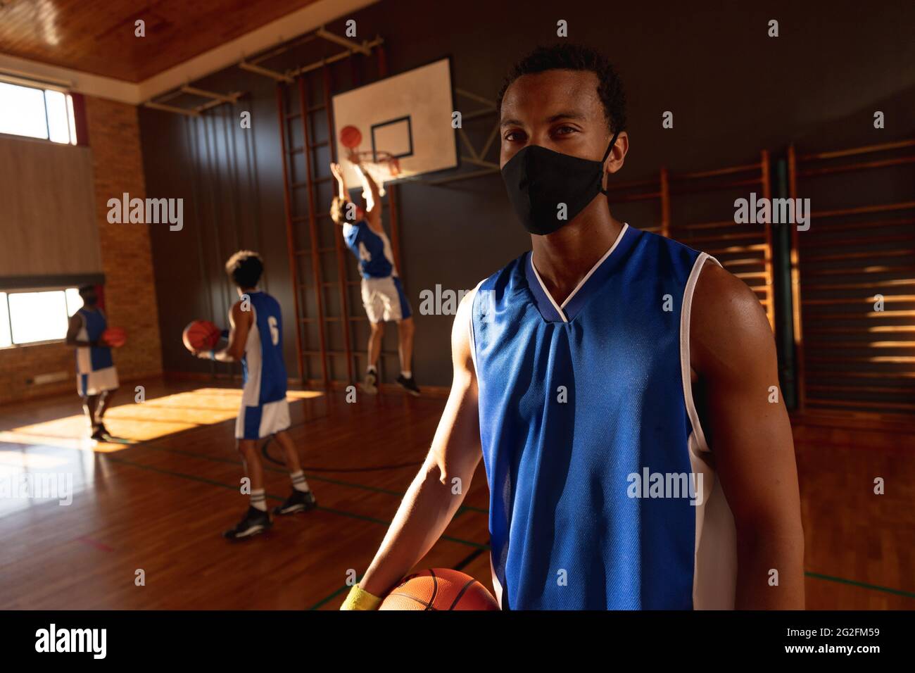 Portrait of mixed race male basketball player wearing face mask with ...