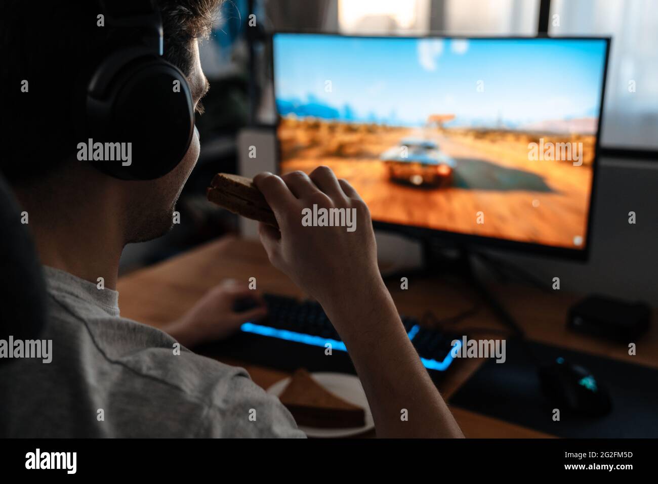Caucasian guy eating sandwich while playing video game on his computer ... Caucasian guy eating sandwich while playing video game on his computer ...