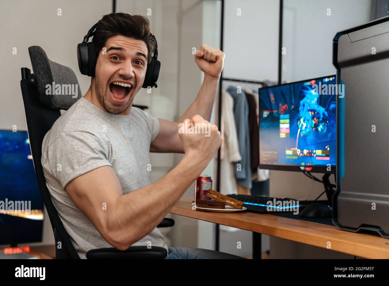 Excited guy in headphones making winner gesture while playing video ...
