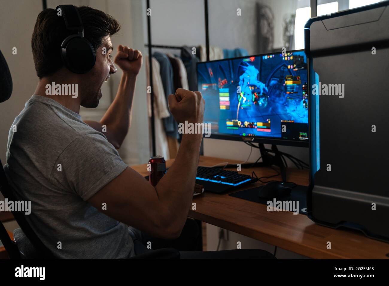Excited guy in headphones making winner gesture while playing video ...