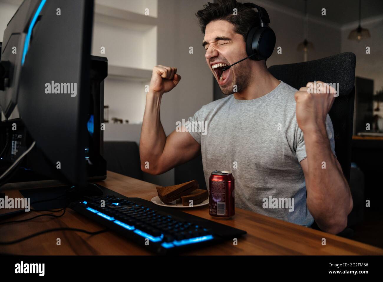 Excited guy in headphones making winner gesture while playing video ...