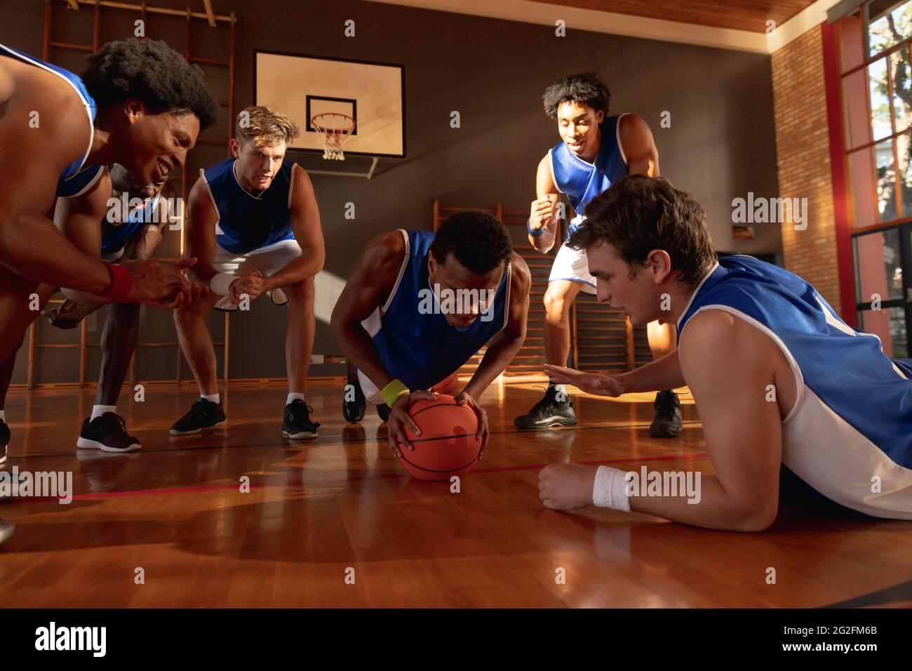Diverse male basketball team wearing blue sportswear and doing push ups ...