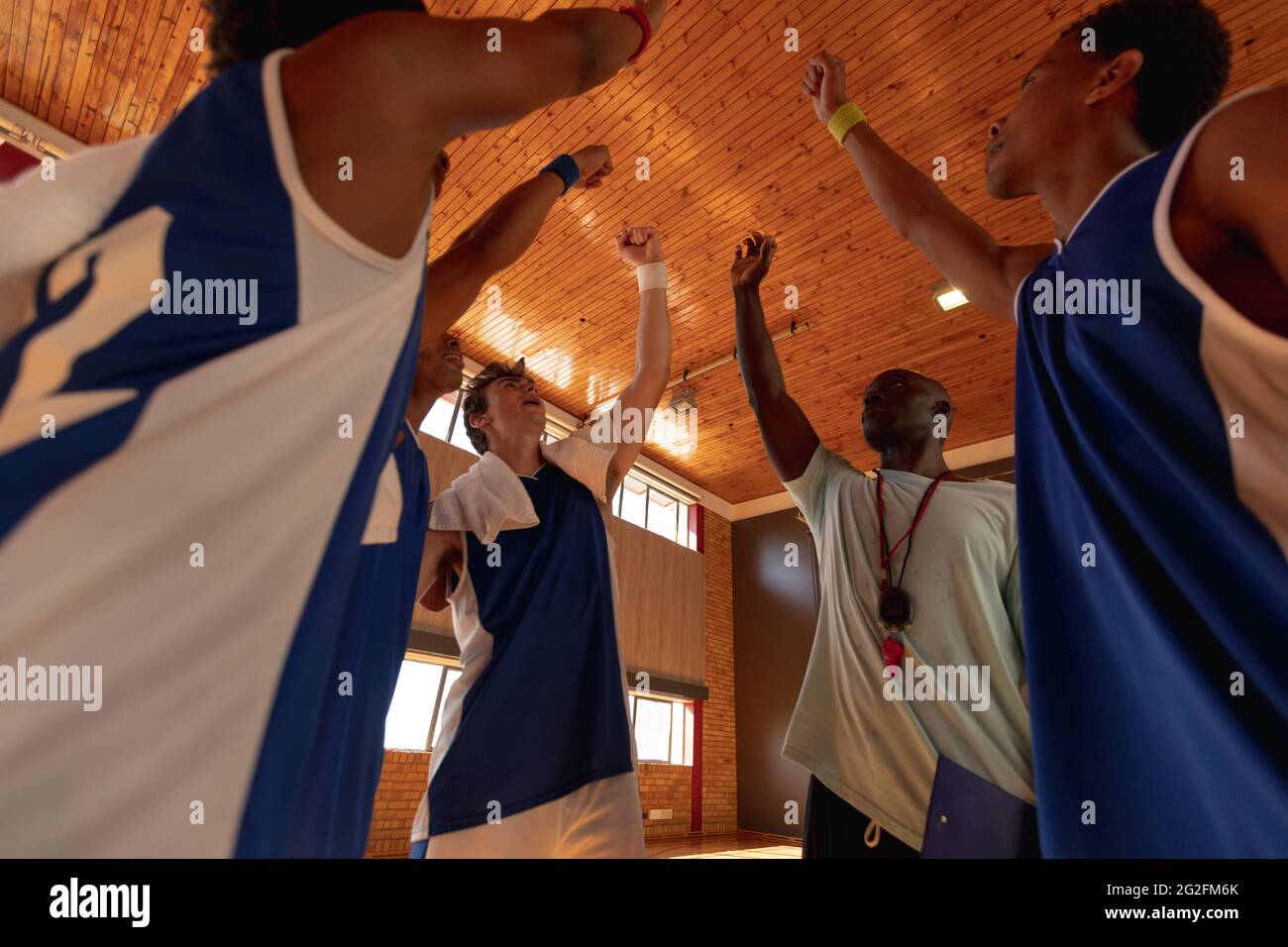 Diverse male basketball team and coach in huddle raising hands Stock ...