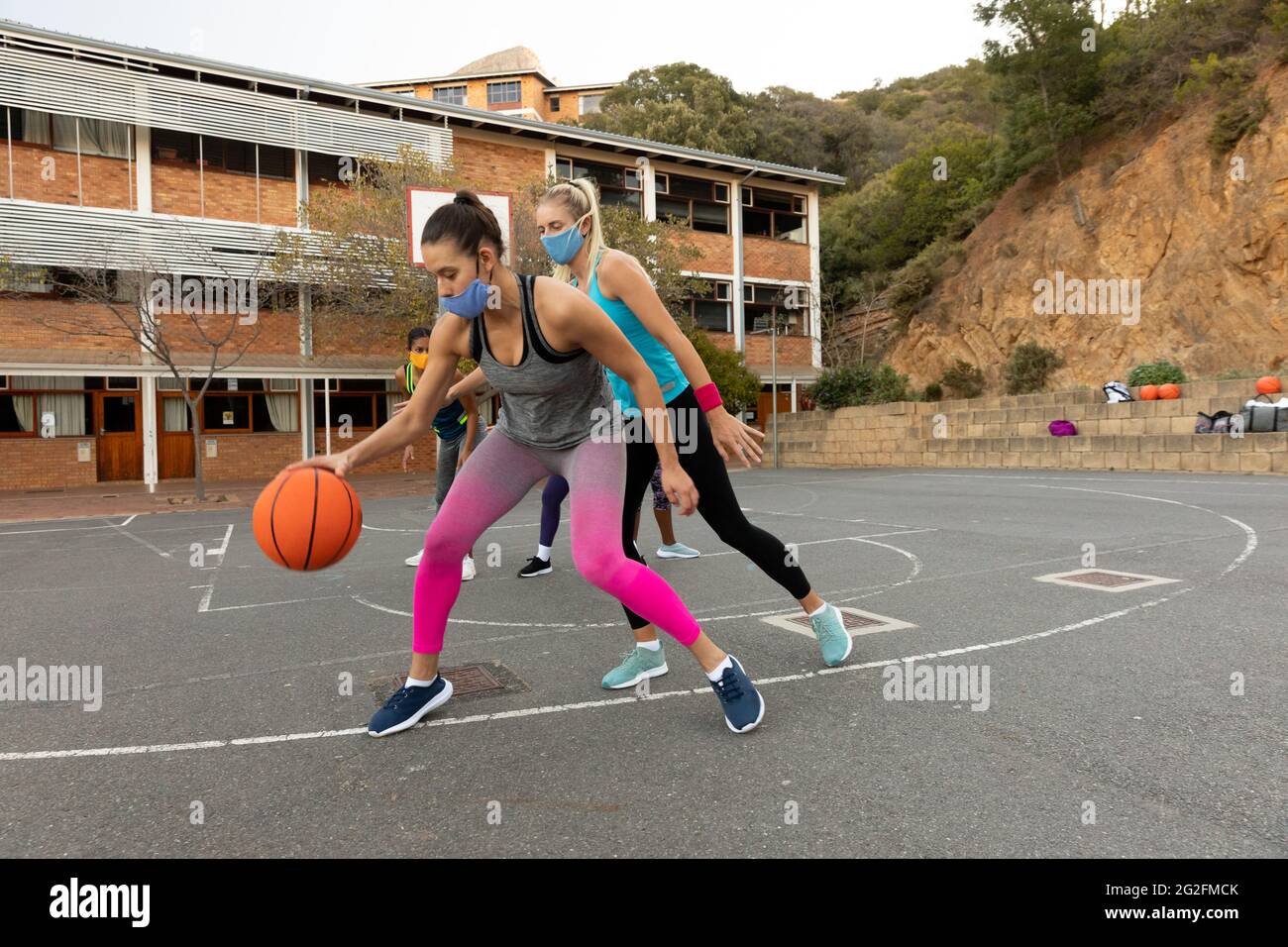 Diverse female basketball team wearing face masks and practice ...