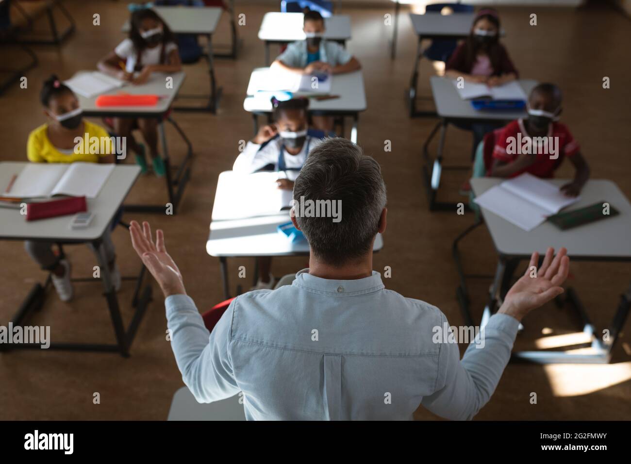 Rear view of caucasian male teacher teaching in the class at school ...
