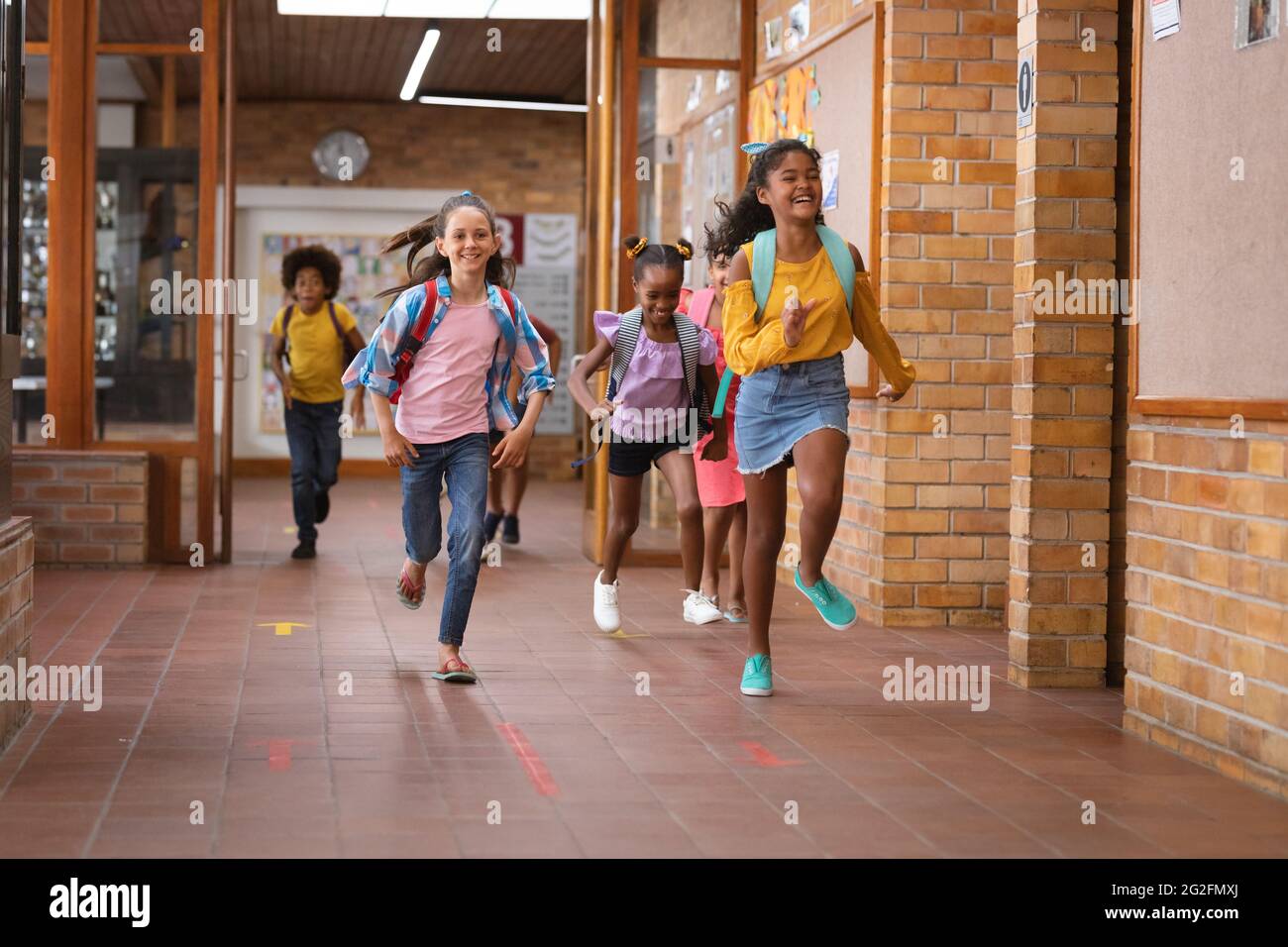 Group of diverse students running together in the corridor at school ...