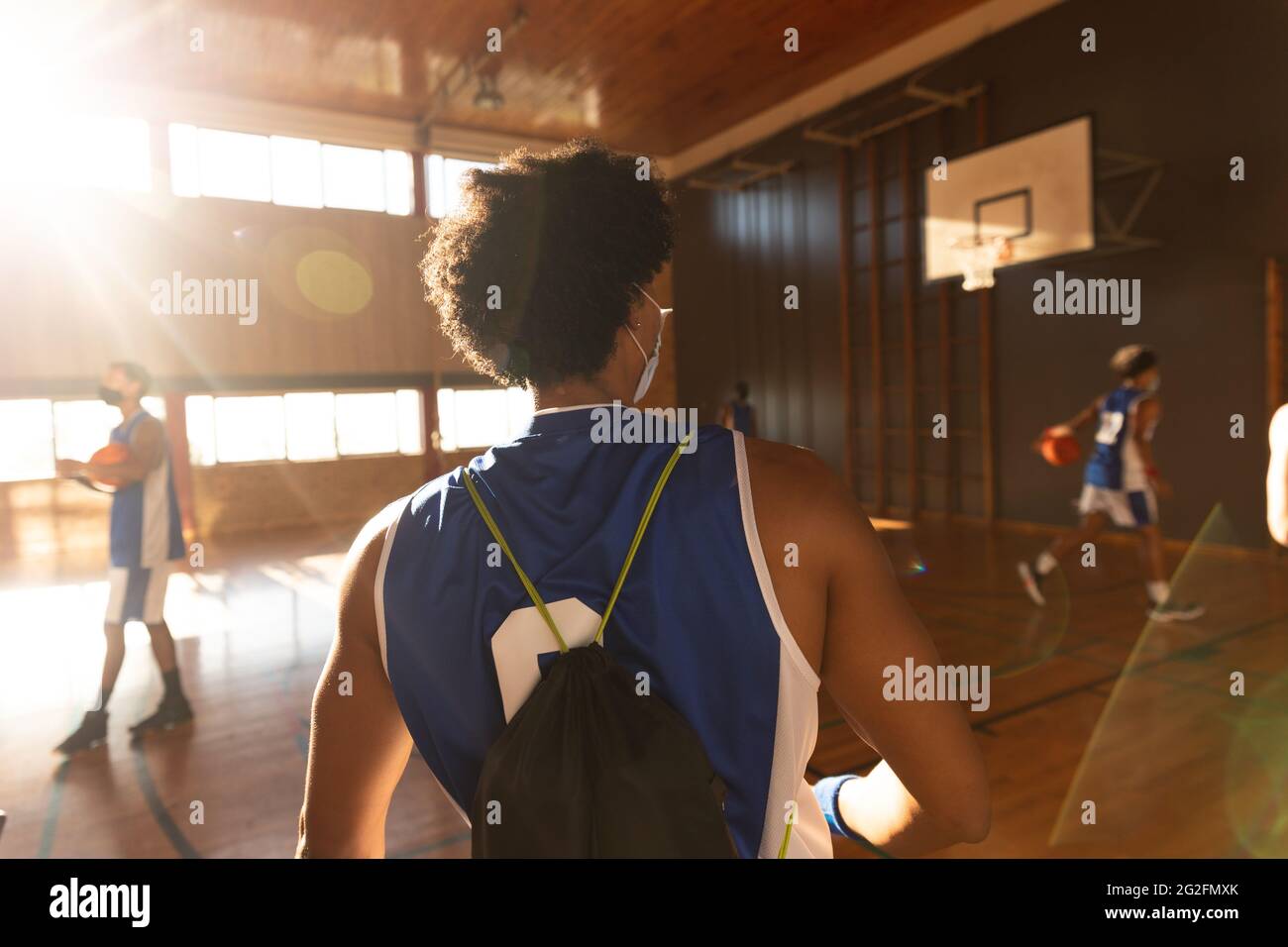 Diverse male basketball team wearing face masks and practicing ...