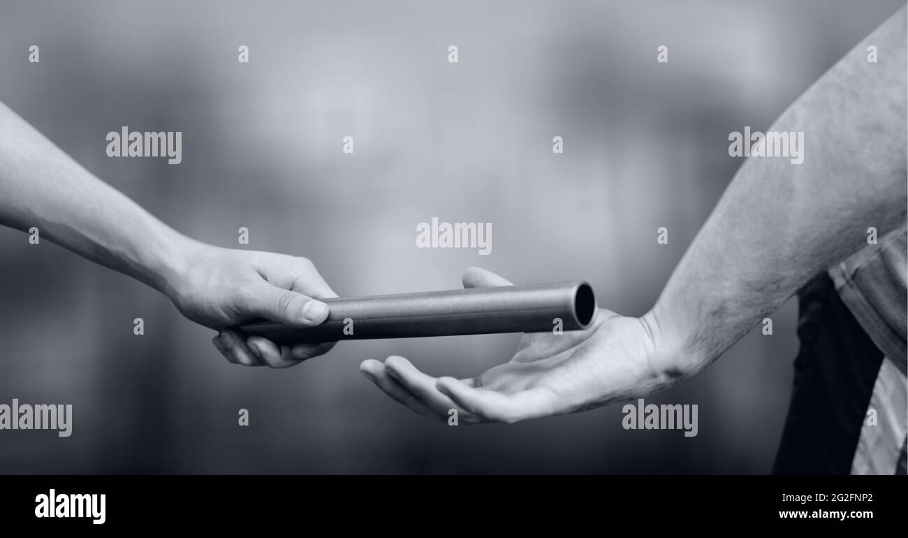 Black and white image of close up of hand passing a baton against grey ...
