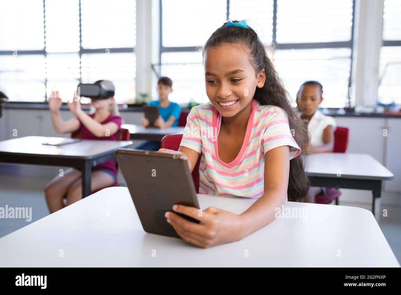 Smiling african american girl using digital tablet while sitting on her ...