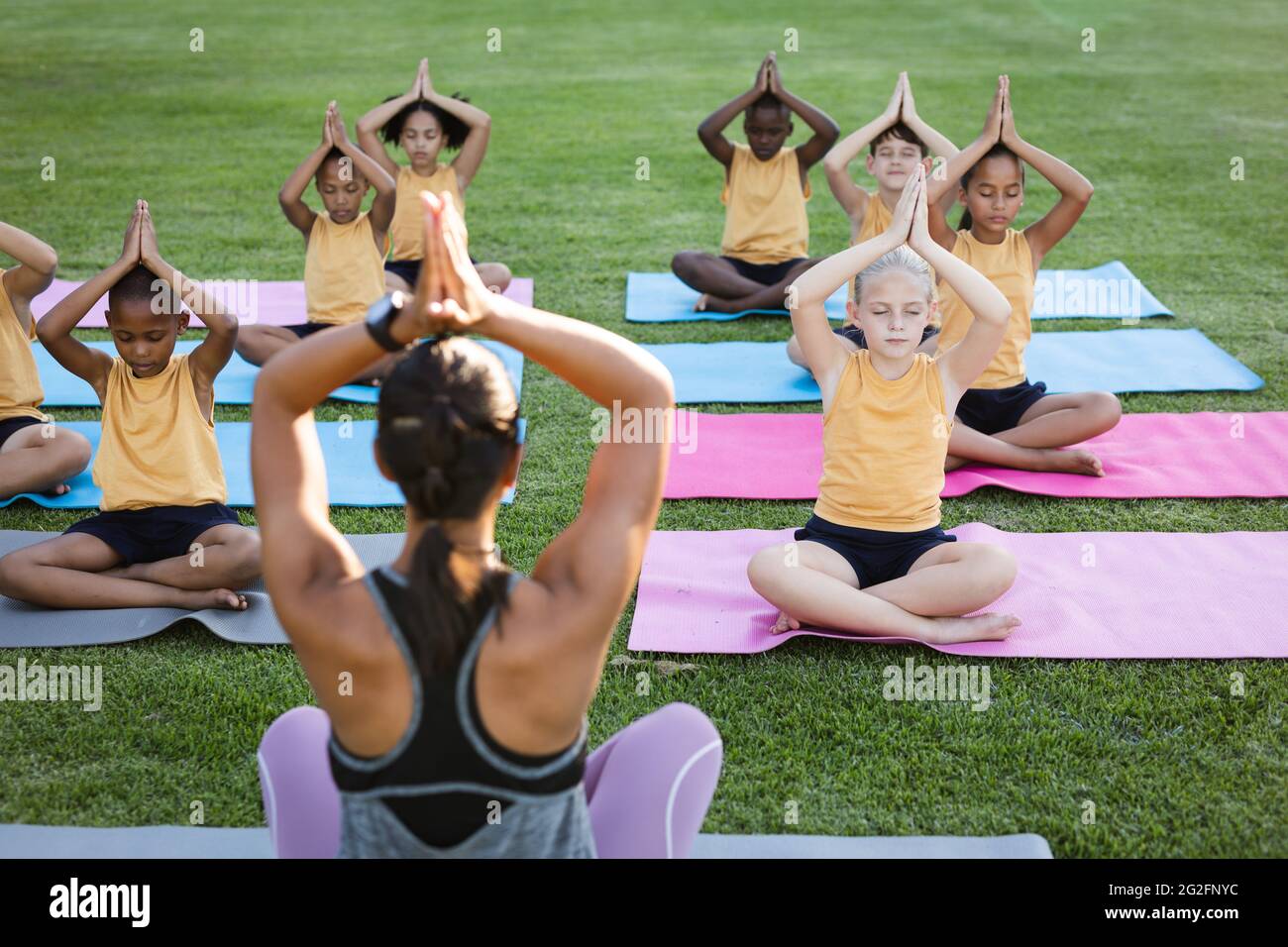 Female teacher and group of diverse students practicing yoga and ...