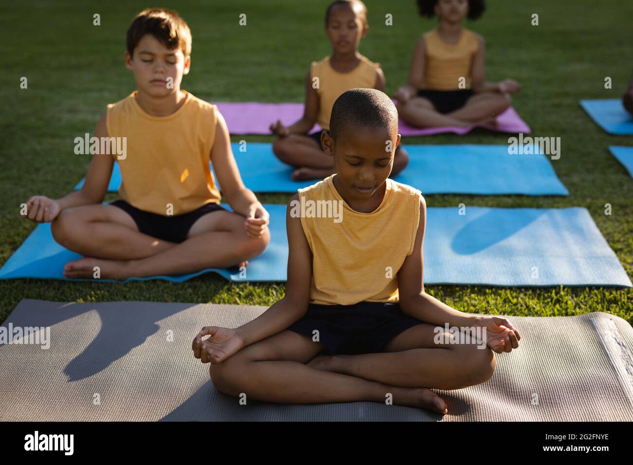Group of diverse students practicing yoga and meditating sitting on ...