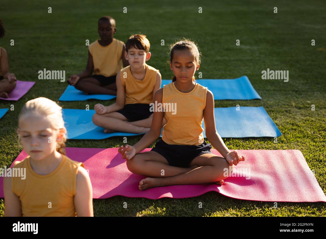 Group of diverse students practicing yoga and meditating sitting on ...
